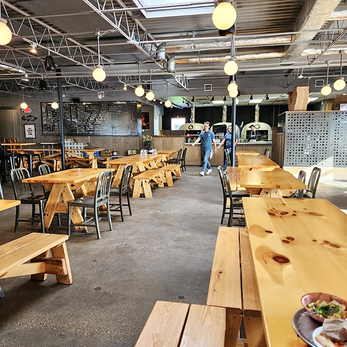 Industrial meets inviting with wooden communal tables and globe lights that cast a warm glow. Pizza tastes better when shared with strangers who become friends.