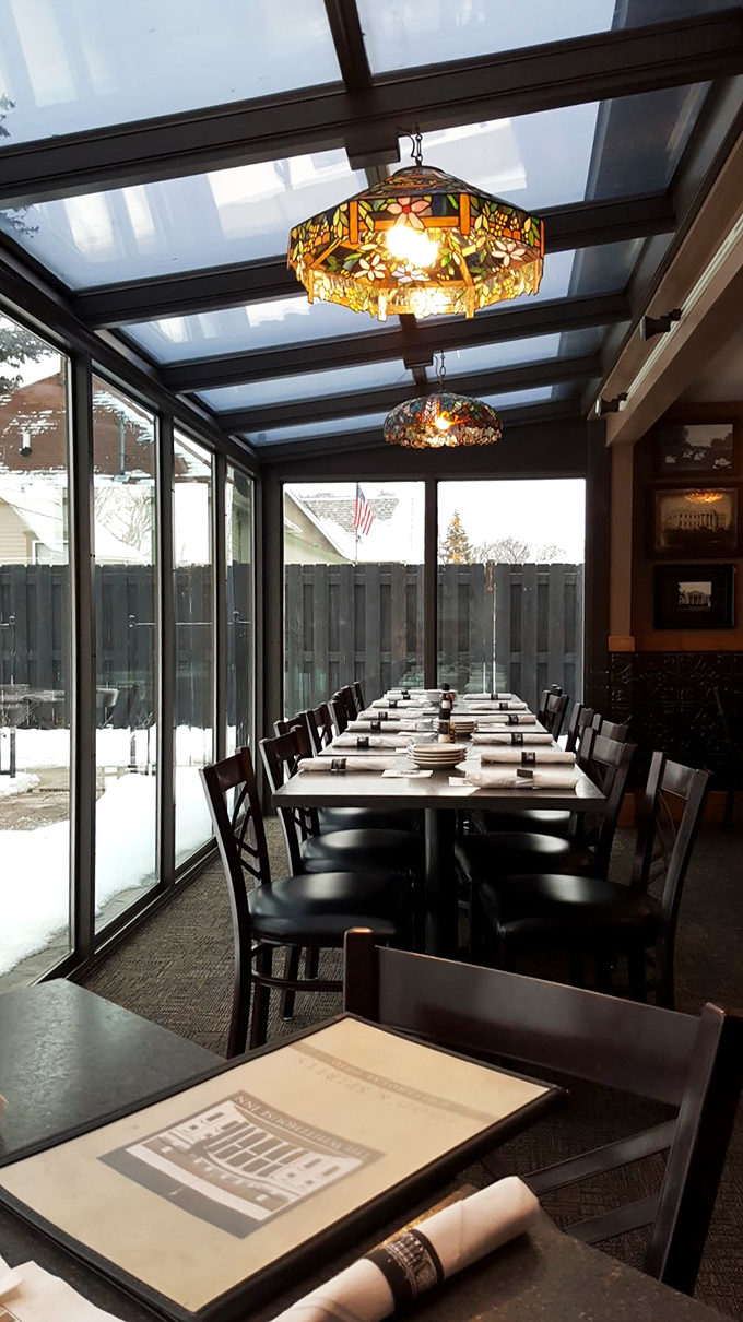 Stained glass pendants cast a warm glow over the sunroom dining area, turning ordinary Tuesday dinners into special occasions worth remembering.