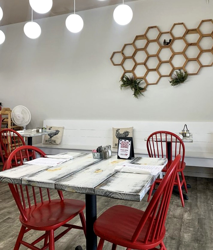 Red Windsor chairs pop against whitewashed tables beneath a honeycomb wall display &ndash; farmhouse chic that doesn't try too hard.