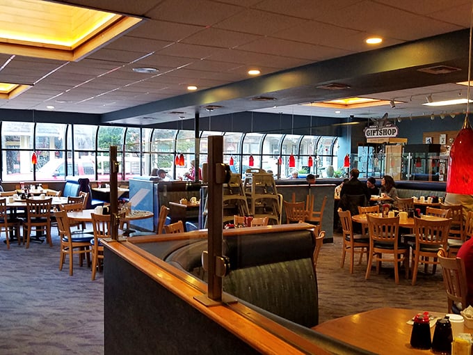 The dining room's curved windows and blue booths create a space where breakfast dreams and ocean views harmoniously coexist.