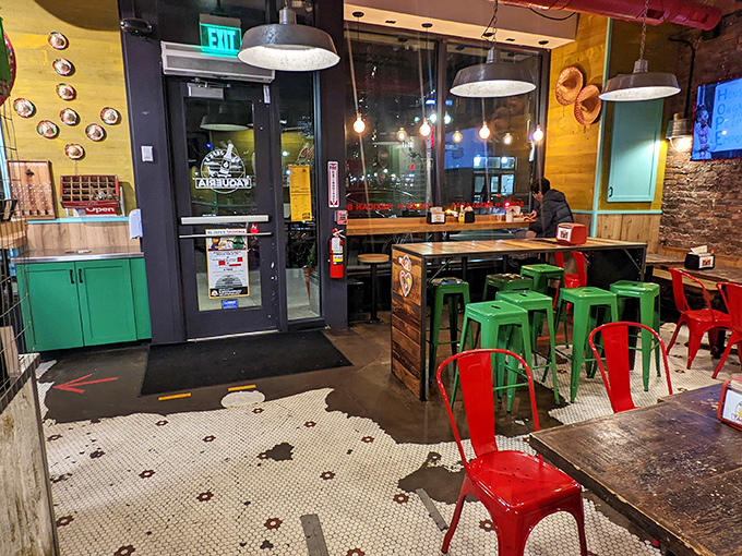 Vibrant red and green metal stools pop against wooden tables, creating a festive atmosphere that says "stay awhile" rather than "eat and run."