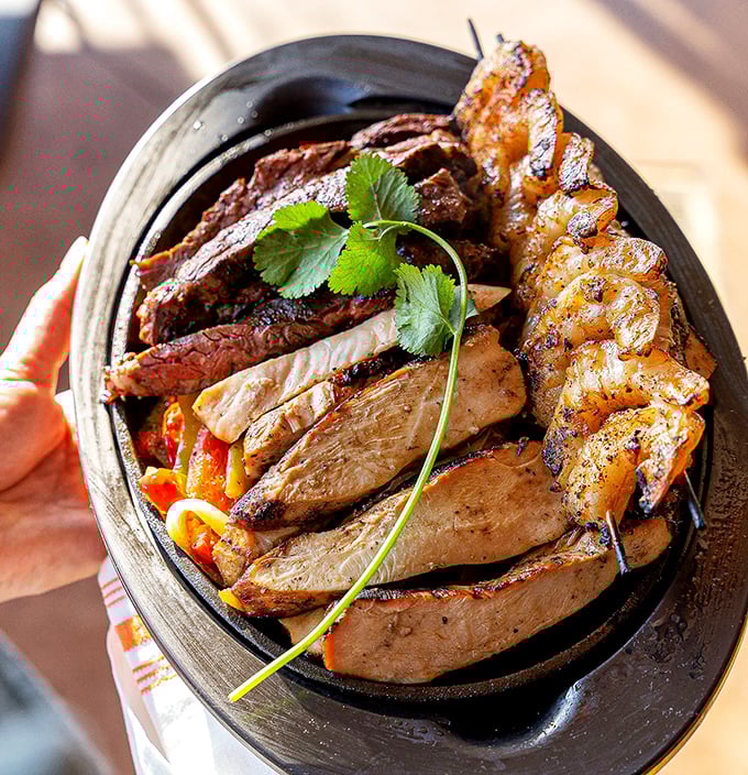 The fajita triple threat &ndash; a sizzling cast iron skillet where beef, chicken, and shrimp perform a smoky, spice-infused dance that's worth the front-row seat.