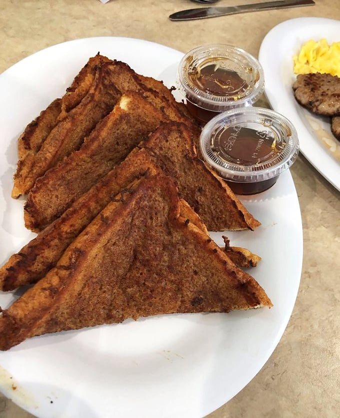 French toast triangles that have clearly been dipped in something magical, served with syrup containers that promise sweet satisfaction.