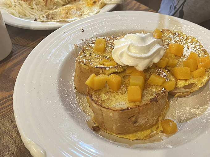 French toast elevated to art form, with mango topping and whipped cream that makes you wonder why anyone bothers with fancy brunch spots.