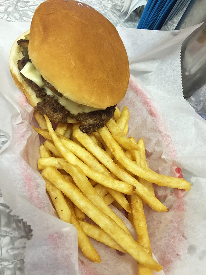 Simple perfection: a hand-formed patty meets melted cheese on a golden bun, with fries that clearly never saw the inside of a freezer.