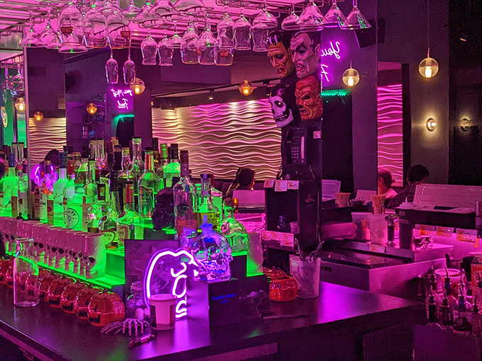 The bar glows like something from a sci-fi film where the drinks might give you superpowers. The neon bottles create an otherworldly atmosphere.