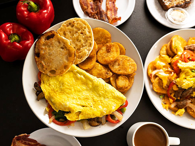 An omelet that refuses to be basic, stuffed with vibrant peppers and accompanied by golden home fries and English muffins ready for their butter baptism.