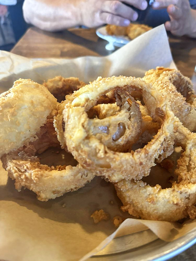Onion rings that achieve the impossible: a crisp exterior that shatters with each bite while protecting sweet, tender onion within.