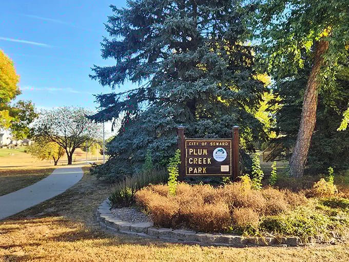 Plum Creek Park's welcoming sign stands sentinel among blue spruces, inviting visitors to explore trails that inspired both feet and literature.