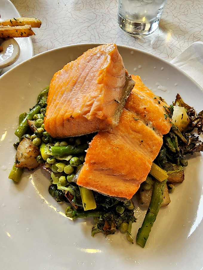 Salmon that looks like it jumped straight from stream to plate, lounging on a bed of vegetables that actually deserve to be eaten, not pushed aside.