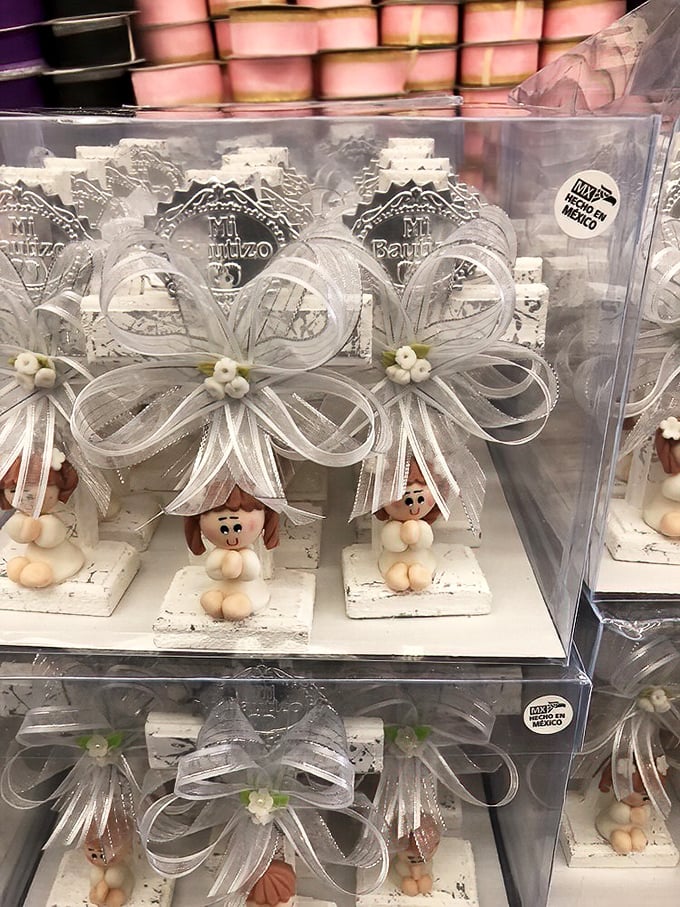Delicate "Mi Bautizo" keepsakes stack neatly in their display cases, transforming an ordinary table into a celebration of life's precious moments.