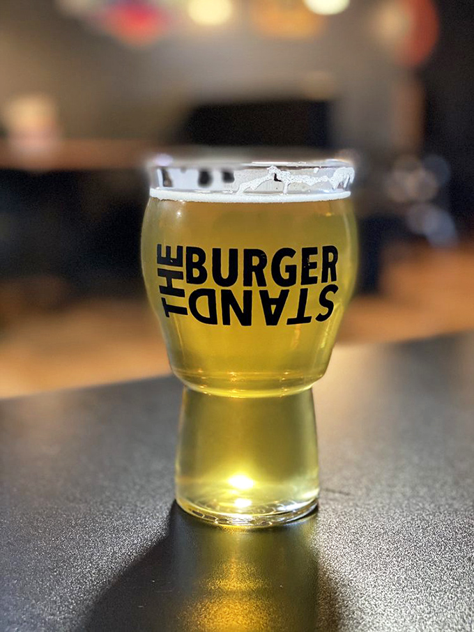 A perfectly poured craft beer sporting The Burger Stand logo—because great burgers deserve equally thoughtful liquid companions.