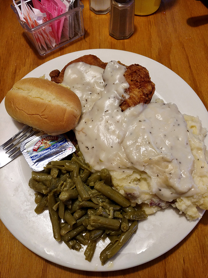 Country fried steak smothered in gravy with green beans and mashed potatoes—the holy trinity of comfort food that hugs your soul.