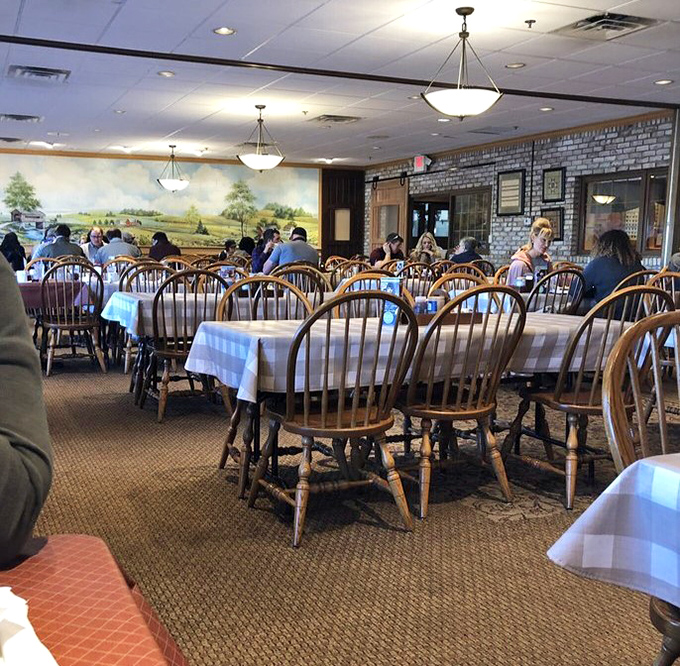 The dining room hums with satisfaction, as wooden chairs cradle happy diners beneath a mural of Amish countryside. Fellowship and food, together.