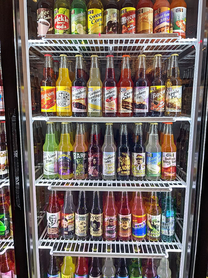 The refrigerated case displays bottles arranged with museum-like precision, each one a tiny carbonated ambassador from another time or place.