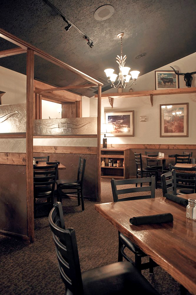 Wooden dividers create intimate dining spaces that say, "Yes, we know steaks are personal business," while cattle-themed art reminds you what's for dinner.