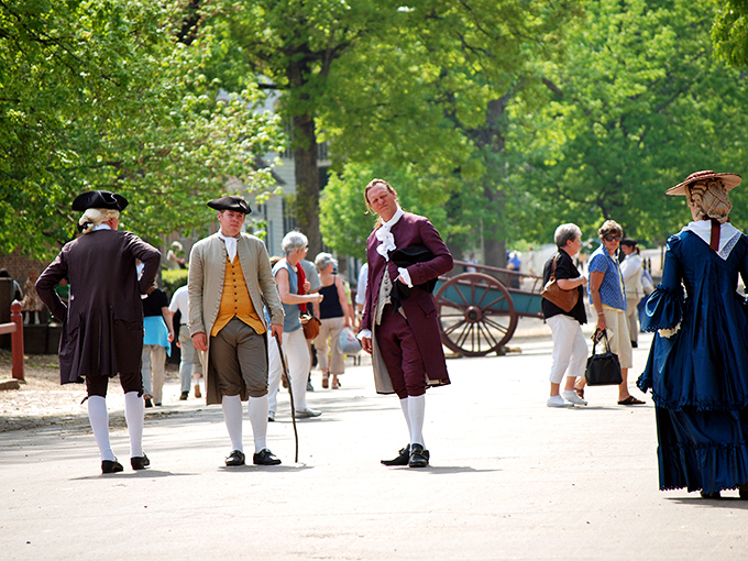 Three gentlemen in waistcoats and knee breeches discuss matters of state while modern tourists in shorts wonder how anyone survived summer in those outfits.