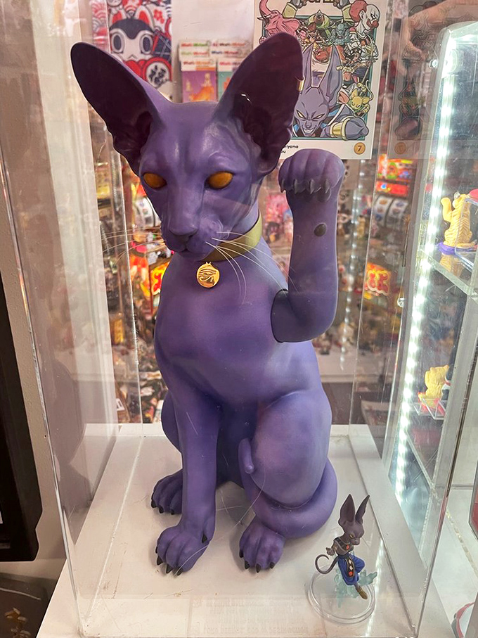 This striking purple sphinx-like cat with glowing amber eyes demonstrates how contemporary artists are reimagining the traditional lucky cat concept.