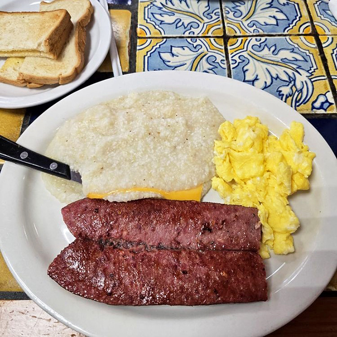 The classic trifecta: eggs, grits, and sausage – proof that sometimes the simplest combinations create the most profound happiness.