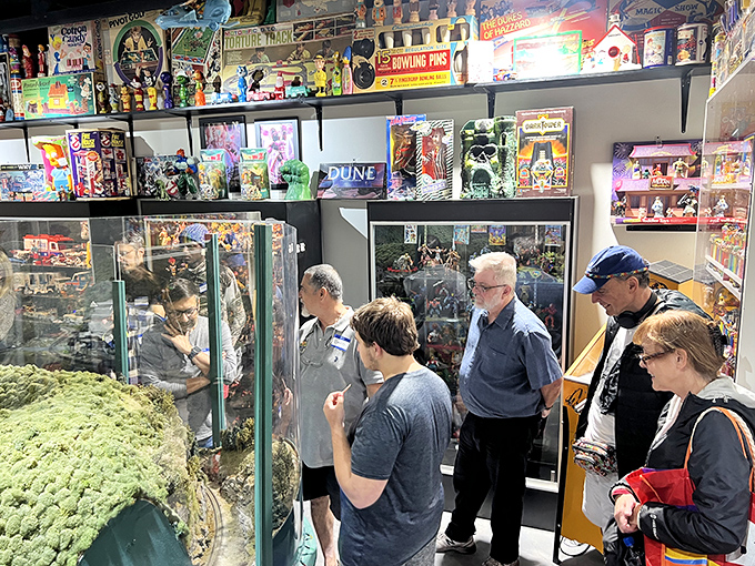 Multigenerational wonder as visitors gather around a detailed display. The shared experience of toy recognition bridges age gaps better than any conversation starter.