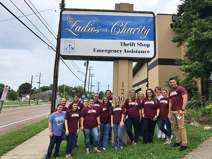 Community spirit meets bargain hunting! Ladies of Charity's sign stands tall as volunteers gather to support their neighborhood thrift mission.