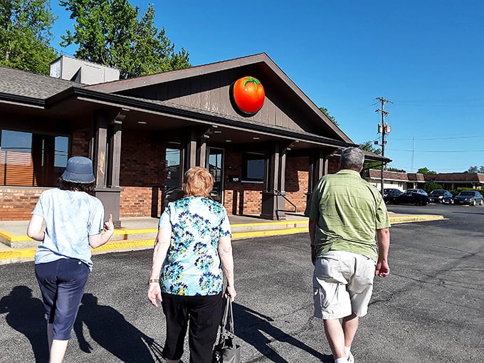 Three people on a pizza pilgrimage – Monical's giant tomato logo means they've reached their delicious destination