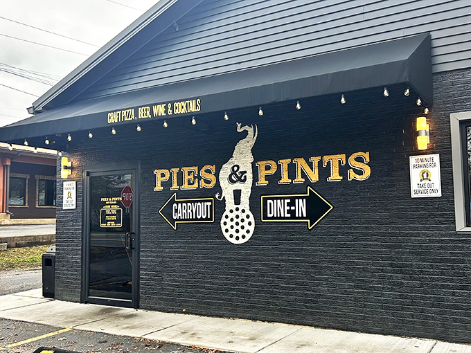Pies & Pints' sleek black exterior with gold lettering offers a modern twist on pizza tradition in the heart of Fayetteville.