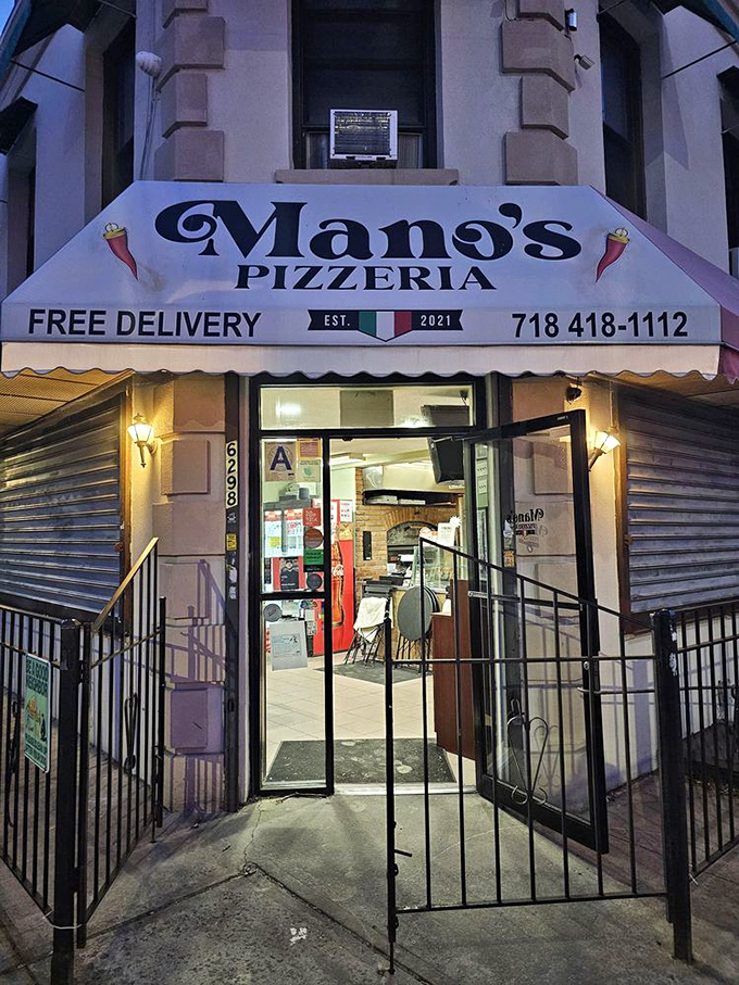 The illuminated entrance to Mano's beckons like a portal to a world where calories don't count and cheese stretches forever.