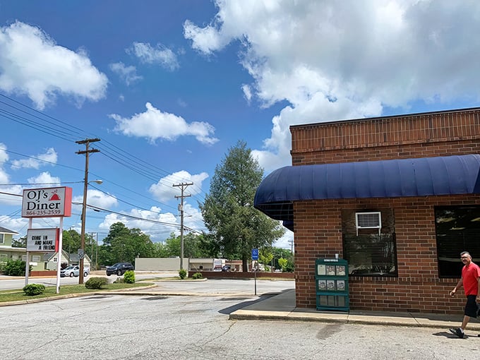 The unassuming brick exterior with that signature blue awning is like a secret handshake among Greenville locals who know where real Southern cooking lives.