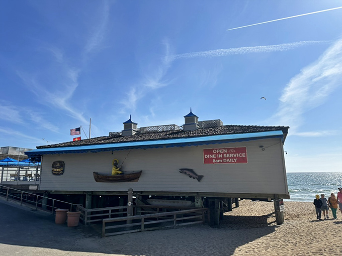 The ultimate beach dining fantasy: a white wooden building perched on stilts above golden sand, with the iconic San Clemente Pier stretching into the Pacific beyond.