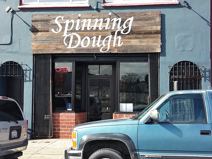 The blue facade of Spinning Dough stands like a culinary speakeasy, its weathered wooden sign promising three essential food groups: pizza, beer, and patio time.