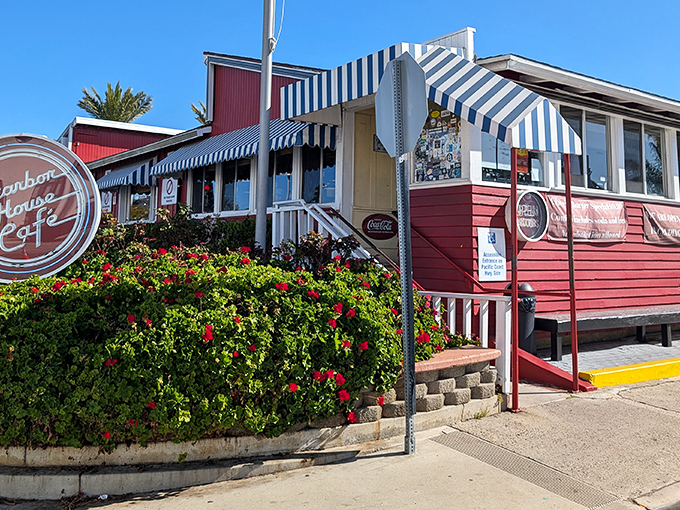 The iconic red exterior with blue-striped awnings stands like a culinary lighthouse on PCH, beckoning hungry travelers with promises of comfort food perfection.