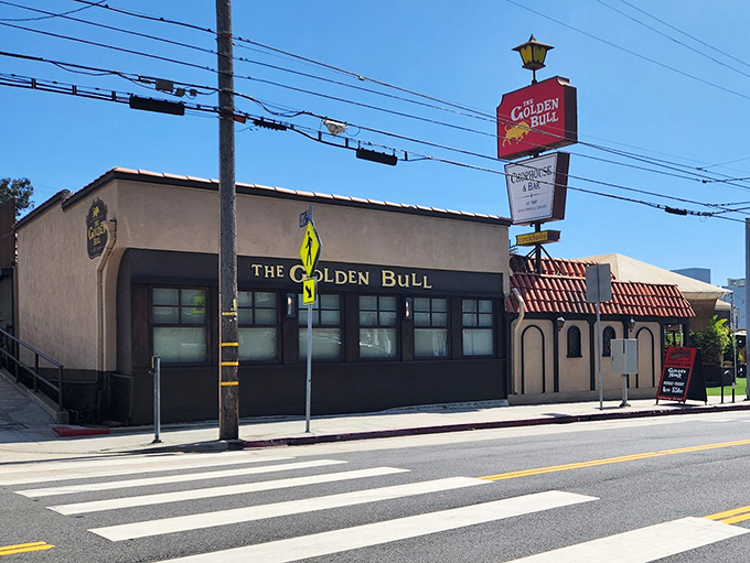 The iconic red sign beckons like a lighthouse for hungry souls. Spanish-style roof tiles and warm lighting promise an authentic California steakhouse experience.