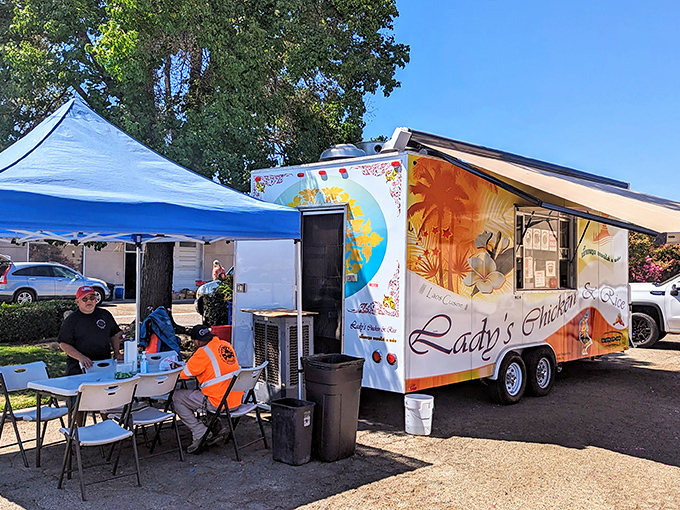 The humble white food truck with vibrant orange accents stands like a beacon of flavor under Central Valley sunshine, complete with shaded seating for those who can't wait to dig in.