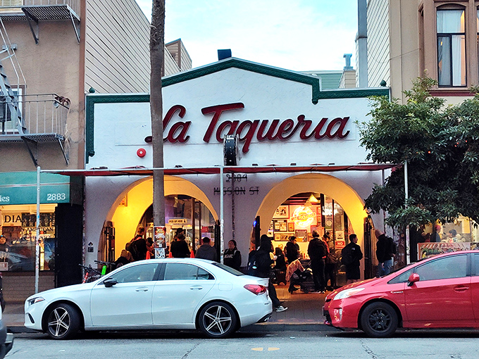 The iconic white facade with red script signage stands like a beacon of burrito brilliance on Mission Street, colorful papel picado dancing in the San Francisco breeze.
