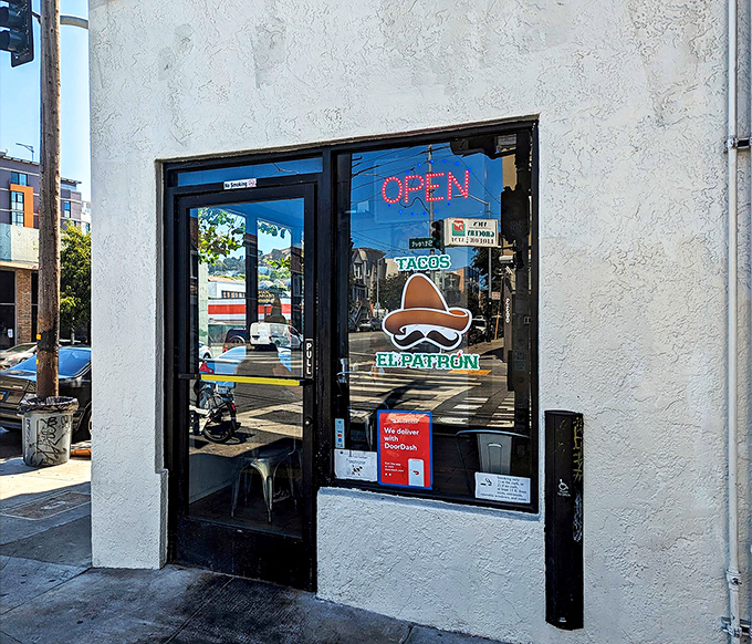 The unassuming storefront of Tacos El Patron beckons with its neon "OPEN" sign and iconic sombrero logo&mdash;proof that culinary treasures often hide in plain sight.