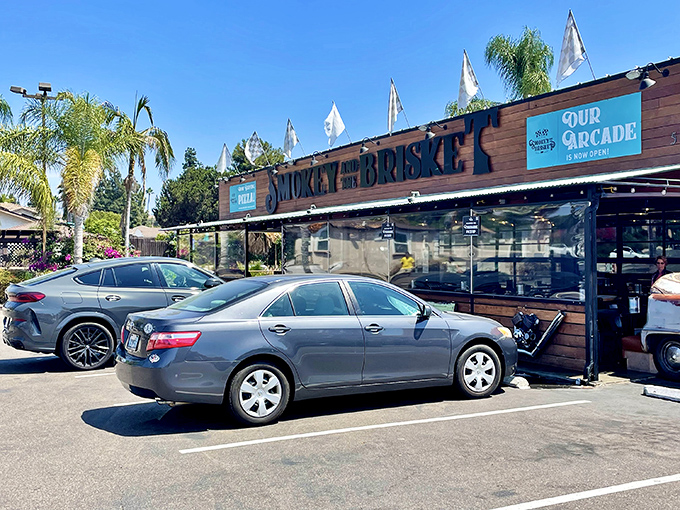 The wooden facade of Smokey and The Brisket stands like a barbecue beacon under the California sun, palm trees swaying as if drawn by the smoky aroma.