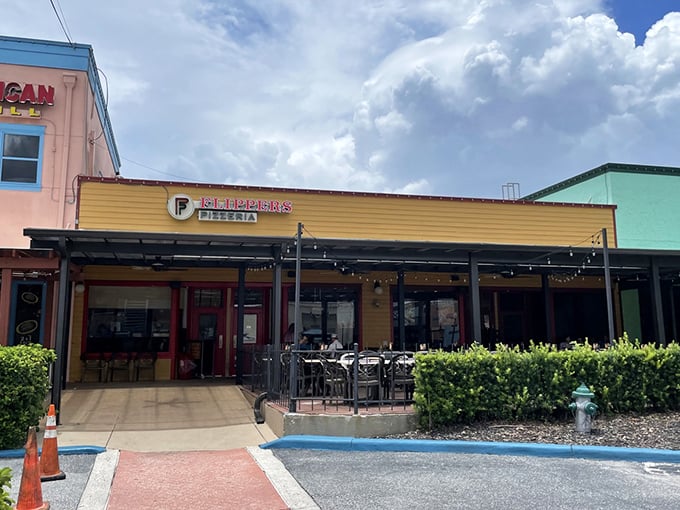 The sunshine-yellow exterior of Flippers Pizza beckons like a carb-loaded oasis in Old Town Kissimmee's colorful landscape.