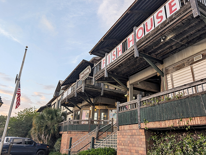 The weathered wooden exterior of The Fish House stands like a sentry guarding Pensacola's seafood treasures, its red lettering a beacon to hungry travelers.