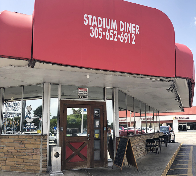 The iconic red awning of Stadium Diner stands out like a culinary lighthouse, beckoning hungry travelers with promises of comfort food paradise.