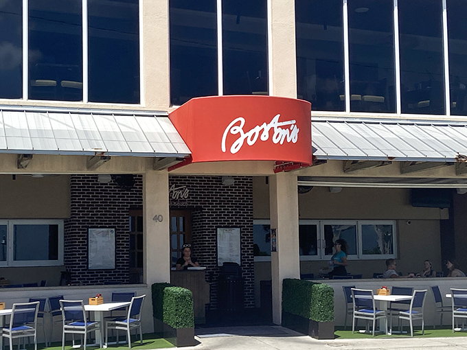 The iconic red "Boston's" sign beckons hungry travelers like a lighthouse for seafood lovers. Beach proximity and cold beer await just beyond those doors.