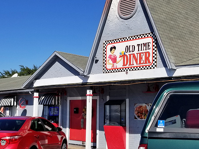 The A-frame entrance to Old Time Diner promises a journey back to simpler times, complete with checkered trim and that classic waitress logo that screams "your calories are about to have a party."