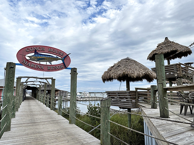The entrance to paradise isn't pearly gates—it's a weathered boardwalk beneath a marlin sign, promising Caribbean flavors just steps away.