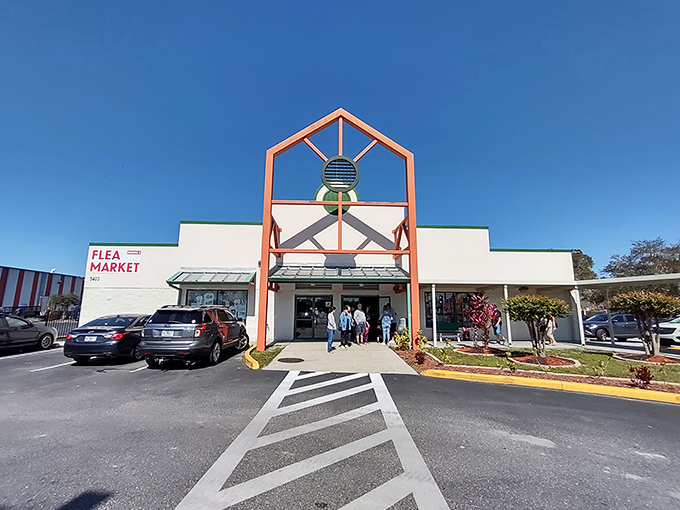 The distinctive orange-framed entrance to Main Gate Flea Market stands like a retail lighthouse, beckoning bargain hunters to the treasures within.