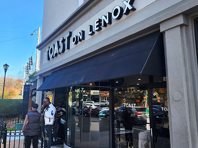 The sleek exterior of Toast on Lenox beckons with understated confidence, its black awning and clean signage promising culinary delights within Atlanta's vibrant Lenox neighborhood.