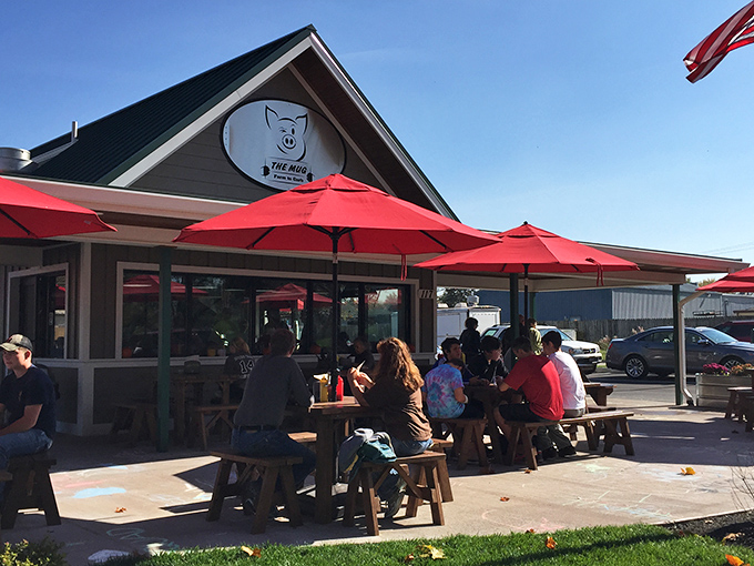 The Mug's inviting exterior with its bright red umbrellas practically whispers, "Come sit a spell." Small-town charm with big-time flavor potential.