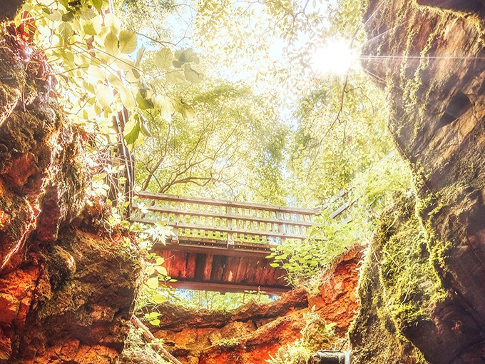 Explorers glide across the emerald waters of Devil's Well, their kayaks illuminated like alien spacecraft beneath the cathedral-like cavern ceiling.