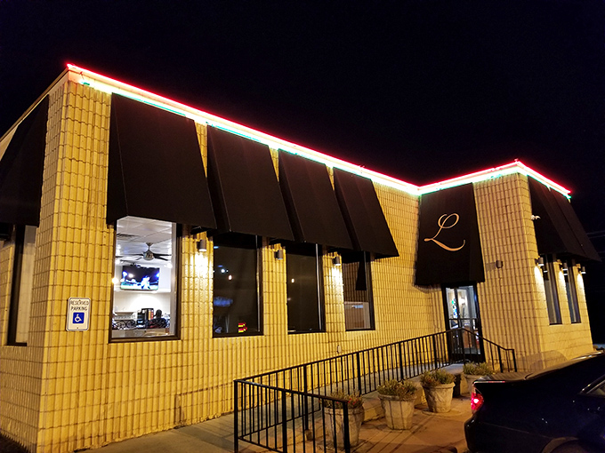 The yellow brick exterior with its distinctive black awnings and red neon lighting transforms into a beacon of comfort food possibilities after dark.