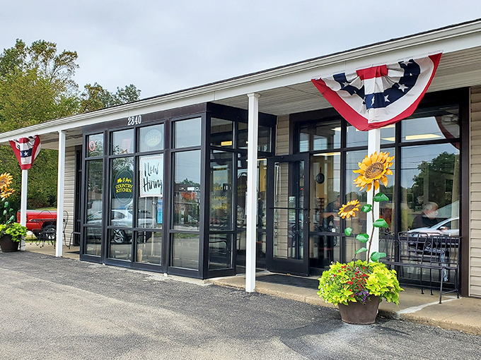 The unassuming exterior of Ma and Pop's Country Kitchen, where patriotic bunting and cheerful sunflowers hint at the warmth waiting inside.