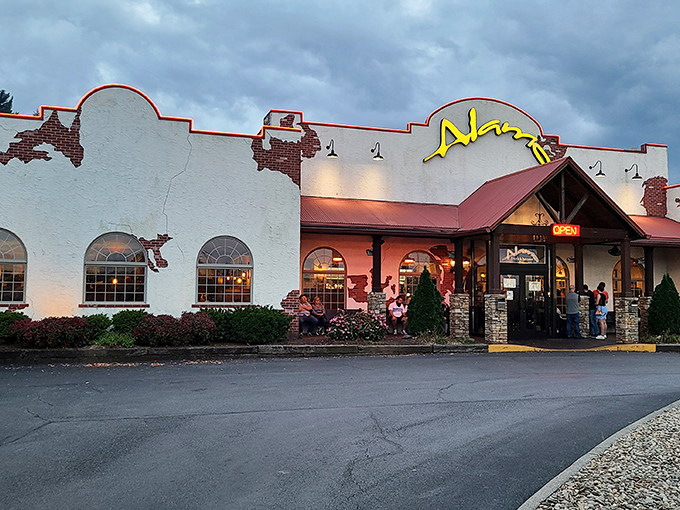 The Alamo Steakhouse's distinctive southwestern facade stands ready to welcome hungry travelers, complete with rustic wagon wheel bench for those inevitable (and worthwhile) wait times.